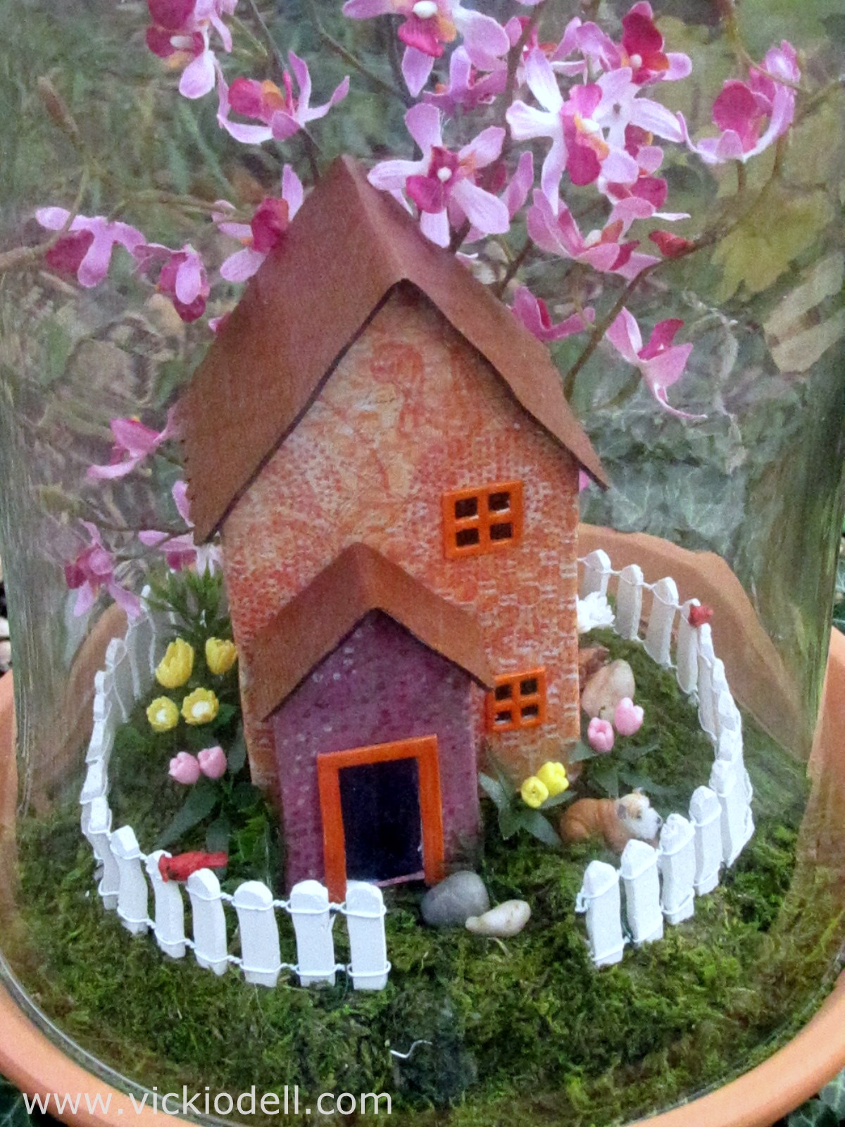 A Miniature House and Garden Under a Cloche